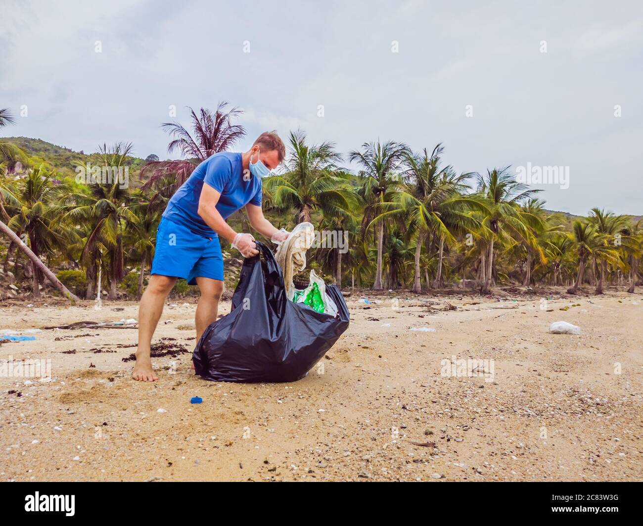 Man in gloves pick up plastic bags that pollute sea. Problem of spilled ...