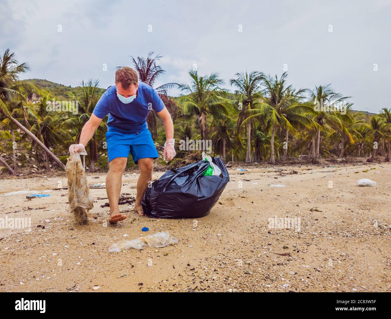 Man in gloves pick up plastic bags that pollute sea. Problem of spilled ...