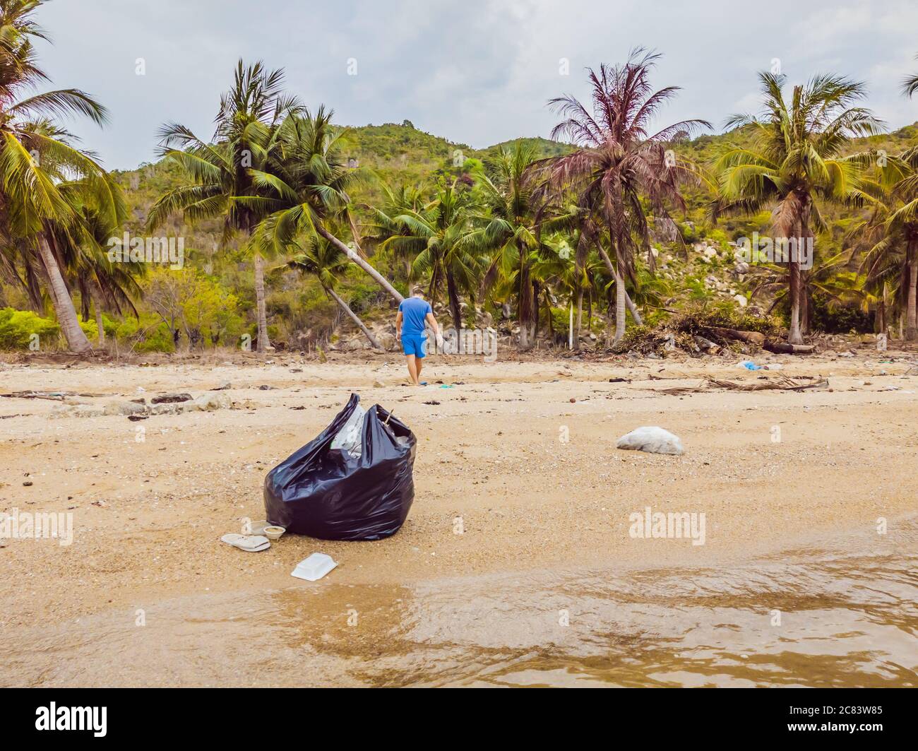 Man in gloves pick up plastic bags that pollute sea. Problem of spilled ...