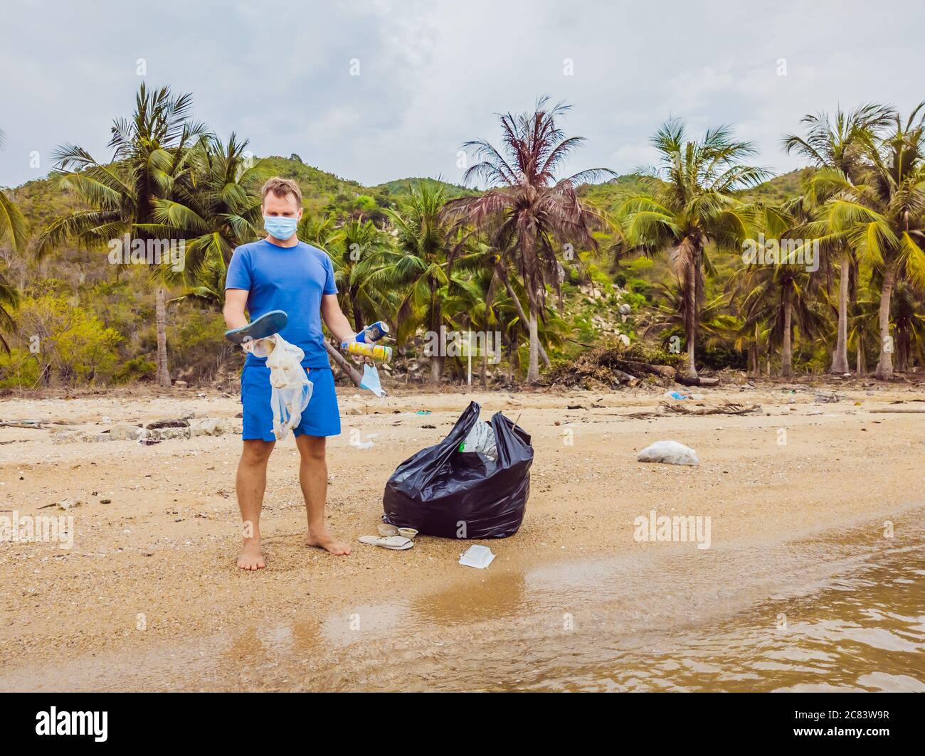 Man in gloves pick up plastic bags that pollute sea. Problem of spilled ...