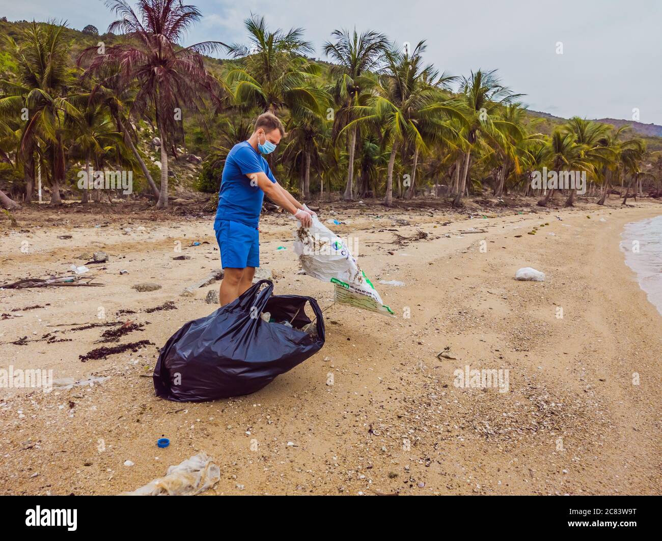 Man in gloves pick up plastic bags that pollute sea. Problem of spilled ...