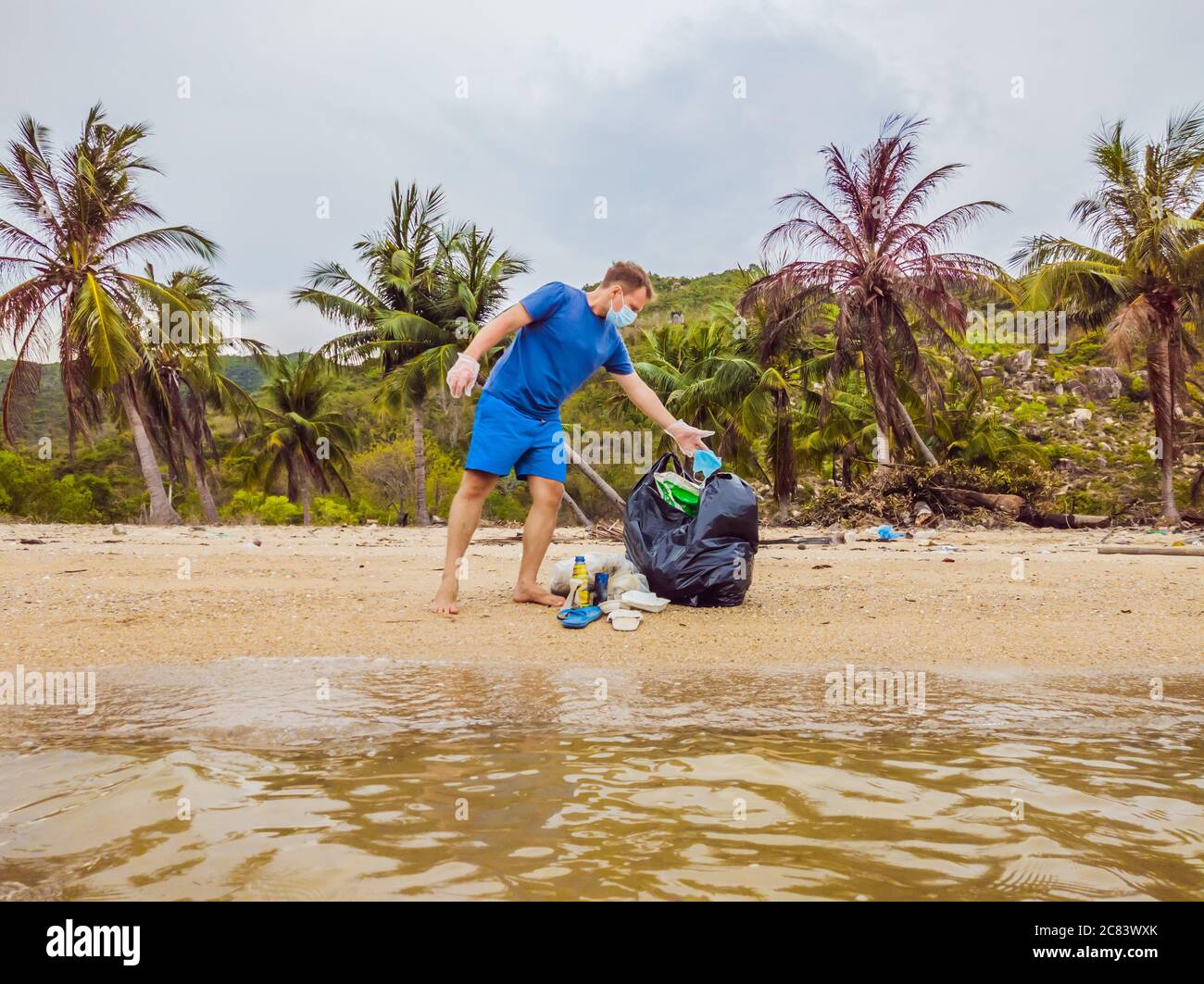 Man in gloves pick up plastic bags that pollute sea. Problem of spilled ...
