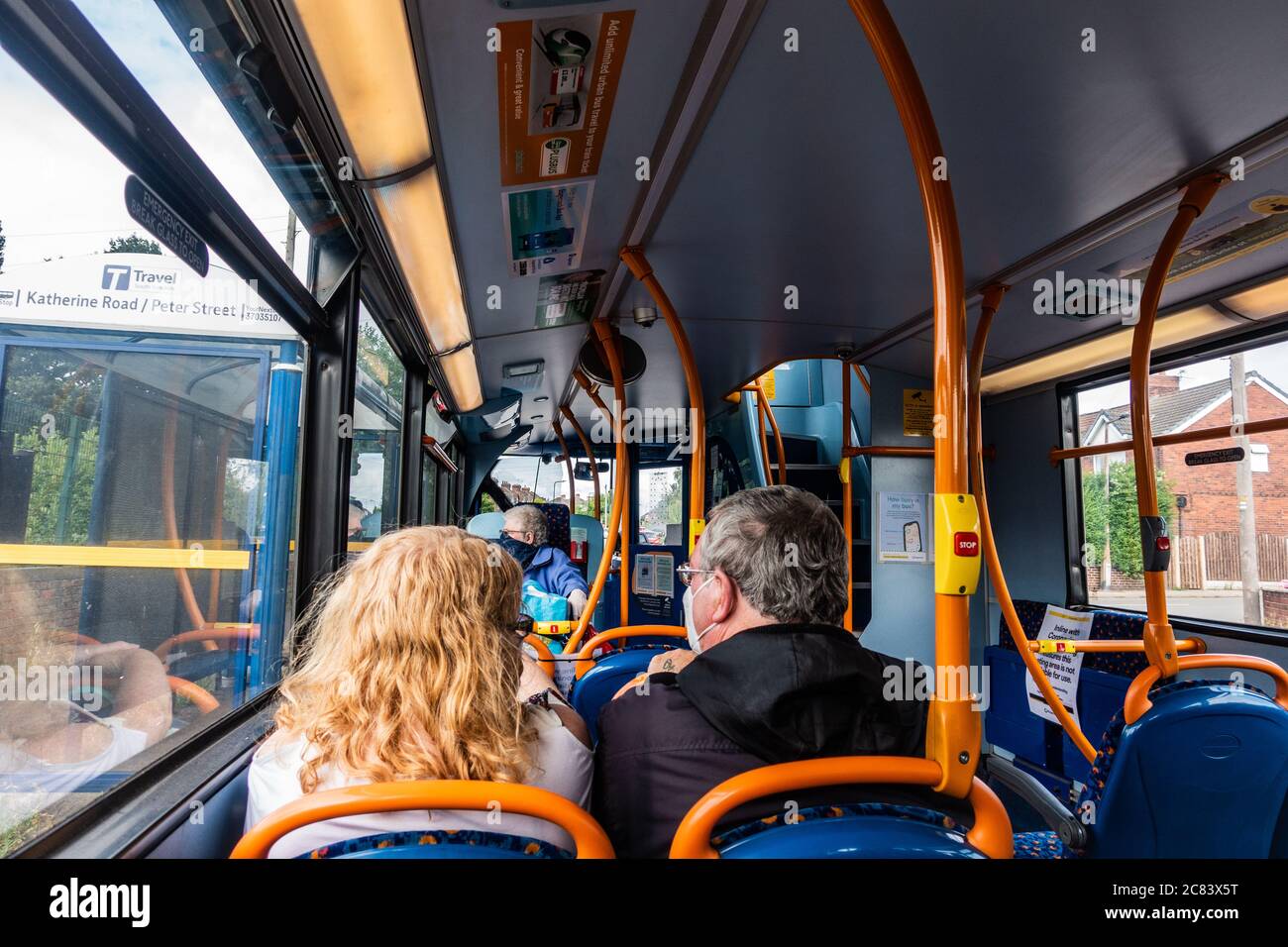 A couple wearing face masks sitting on a bus trip sitting apart during ...