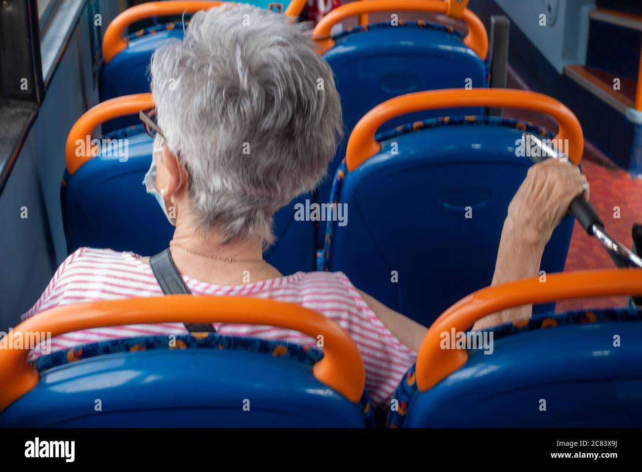 senior citizen lady wearing a face mask sitting on a bus journey ...