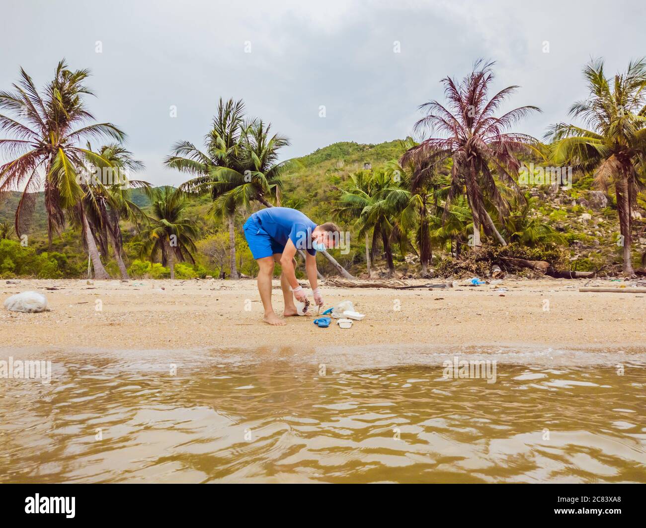 Man in gloves pick up plastic bags that pollute sea. Problem of spilled ...