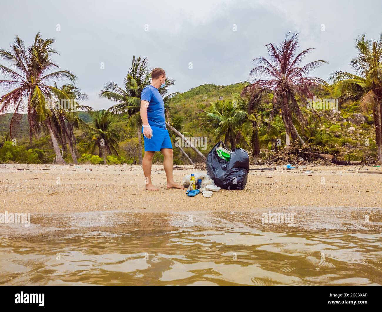Man in gloves pick up plastic bags that pollute sea. Problem of spilled ...