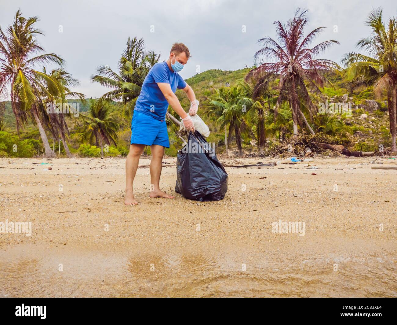 Man in gloves pick up plastic bags that pollute sea. Problem of spilled ...