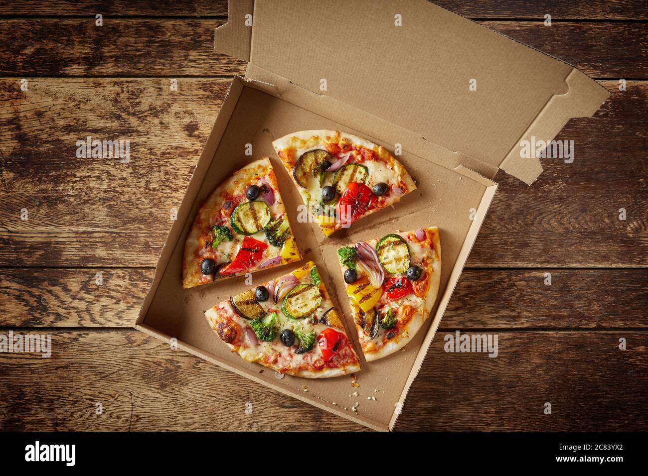 Sliced Italian pizza with fresh vegetables and salami in a cardboard ...