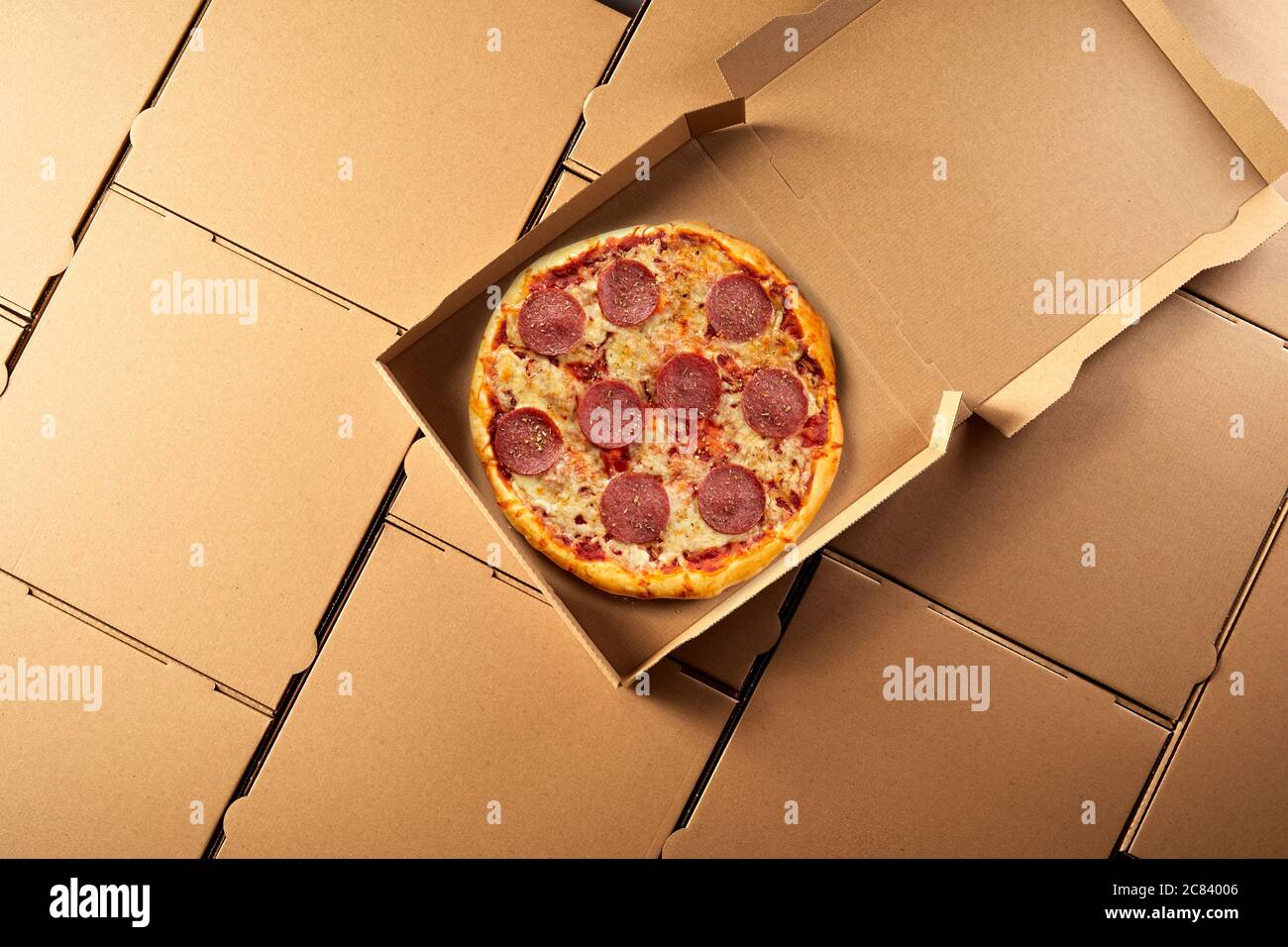 Open takeaway box with freshly made Italian salami pizza inside on a ...