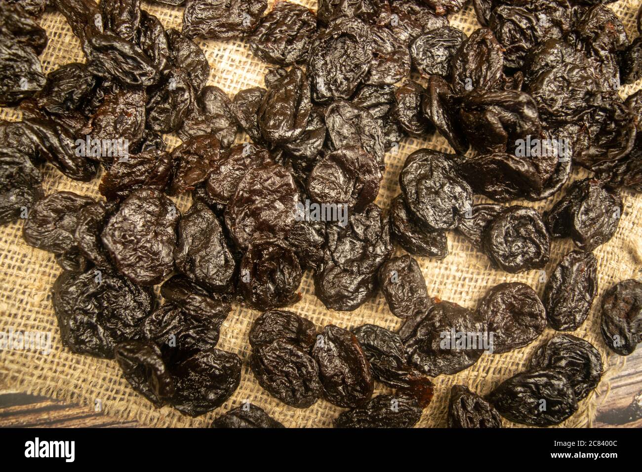 Dried prunes in bulk on burlap with a rough texture. Close up Stock ...