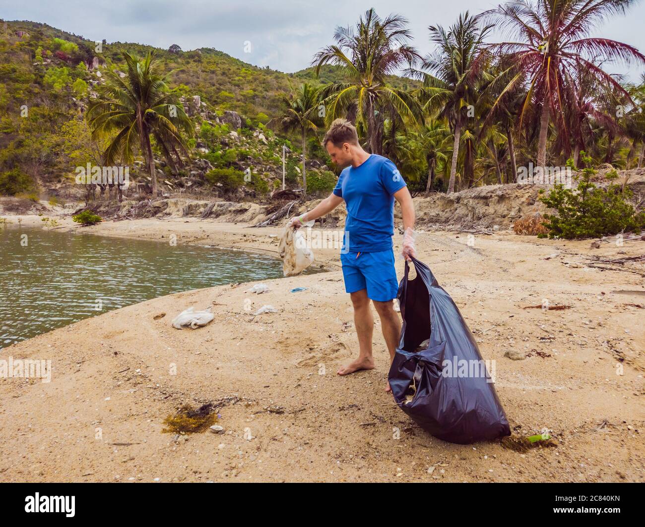 Man in gloves pick up plastic bags that pollute sea. Problem of spilled ...