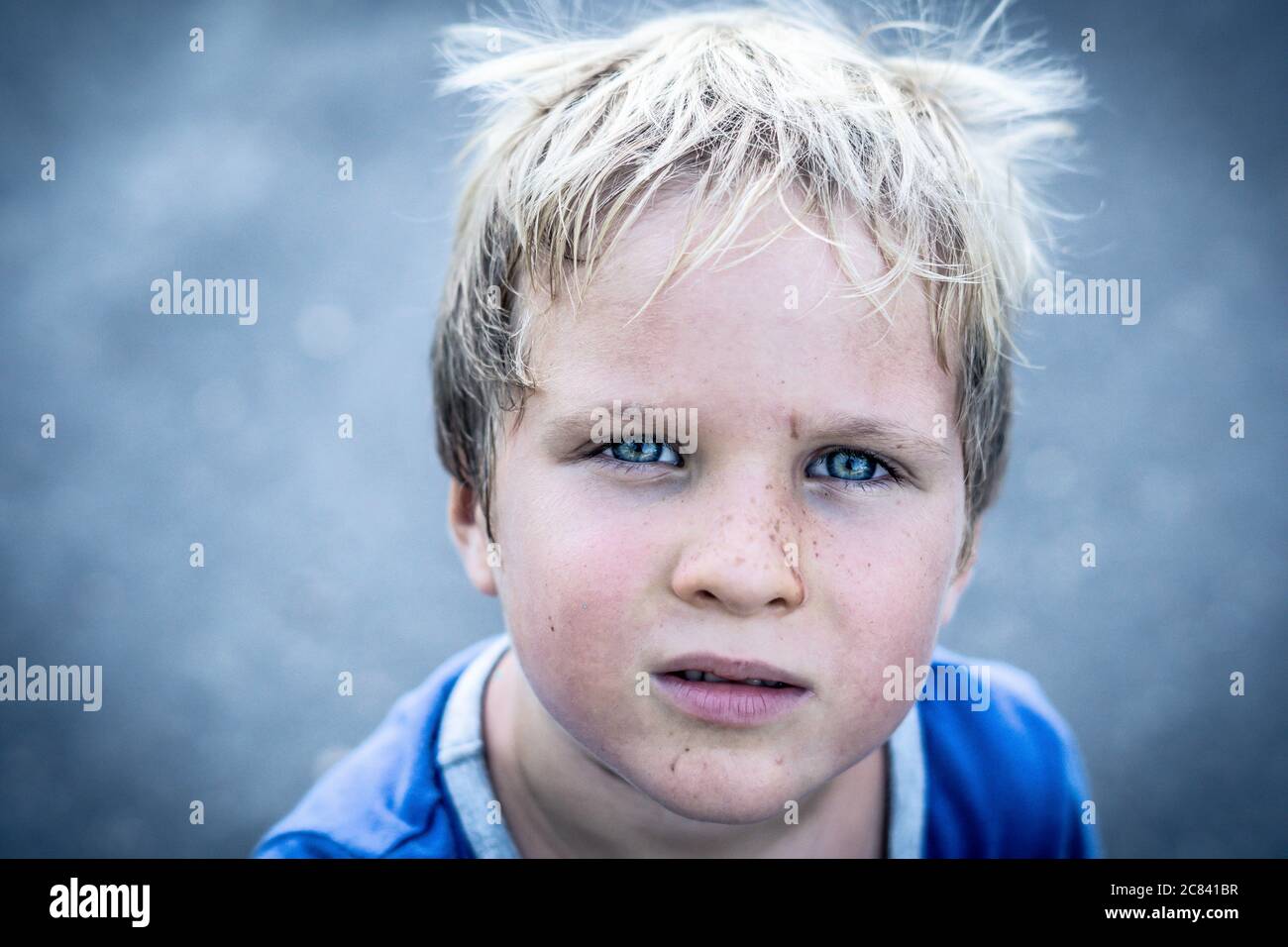 Portrait of a funny happy mischievous cheerful cute blond blue eyed boy ...