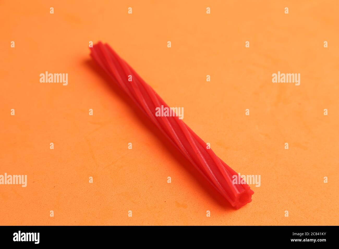 High angle shot of a red licorice stick isolated on an orange ...