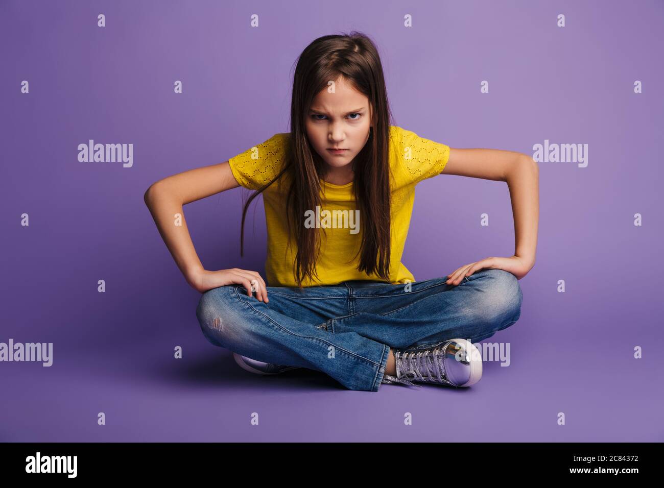 Photo of angry caucasian girl sitting on floor and looking at camera ...