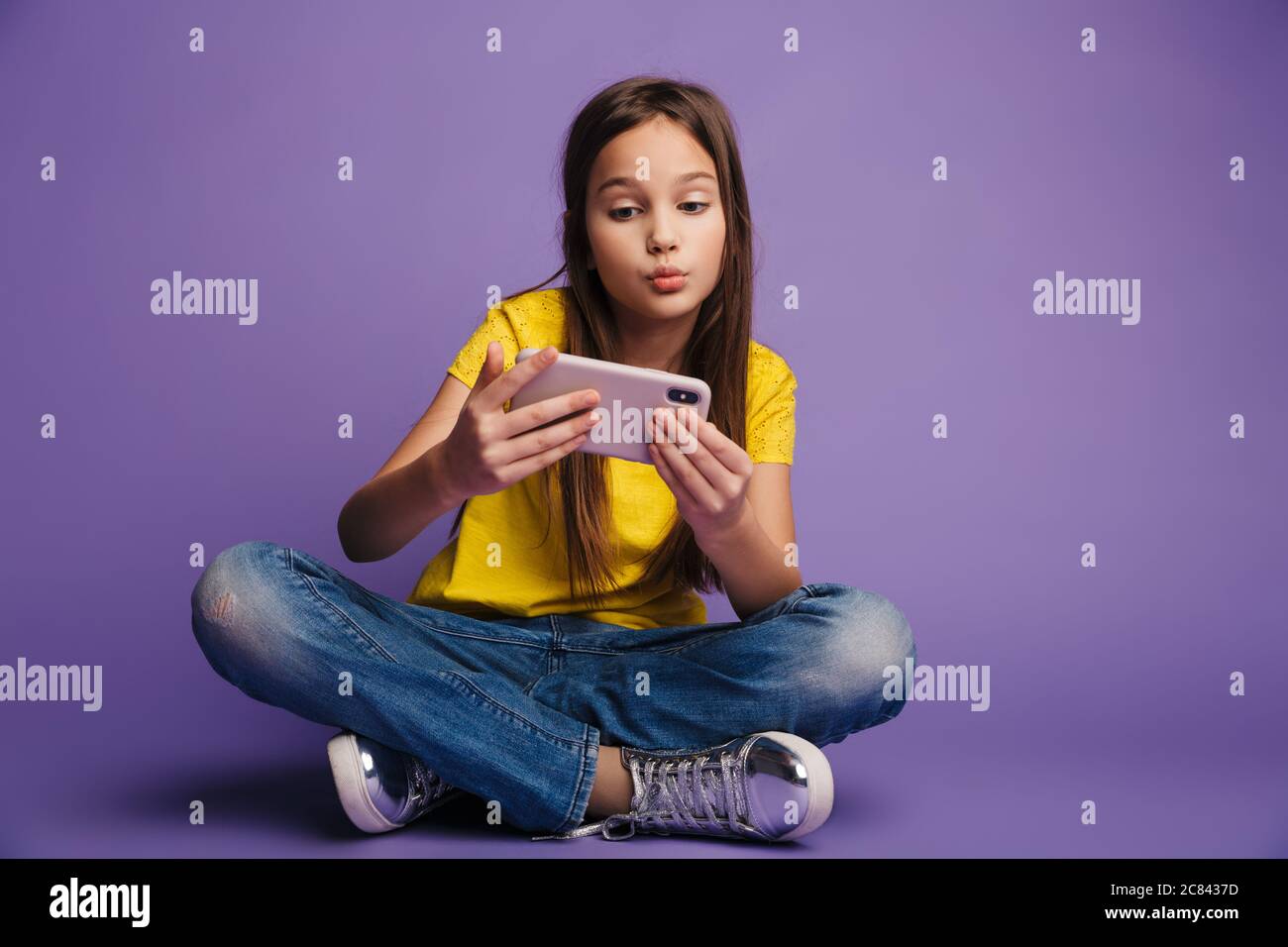Photo of focused cute girl playing video game on cellphone while ...