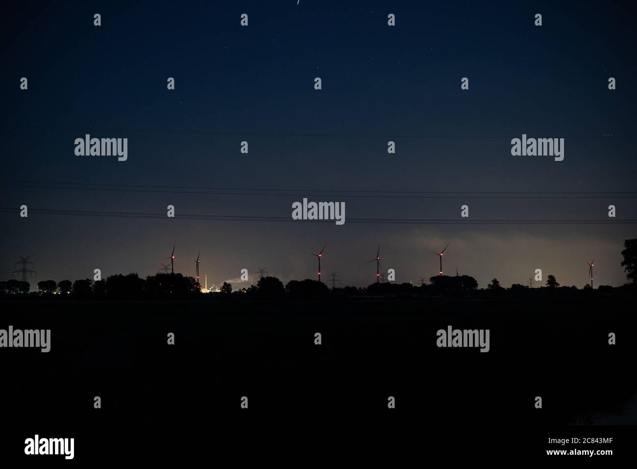 glowing wind turbines with their red lights on the horizon in the dark ...