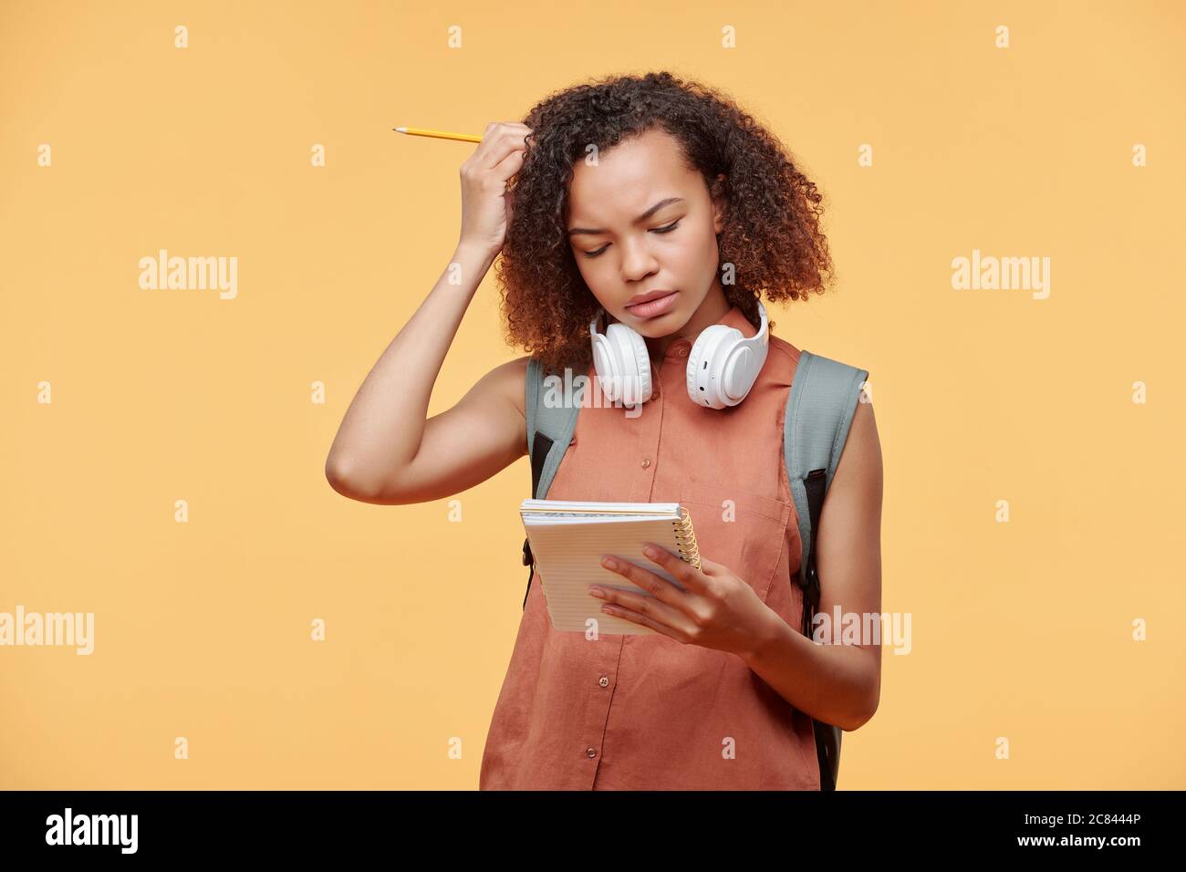 Focused black student girl with wireless headphones around neck ...