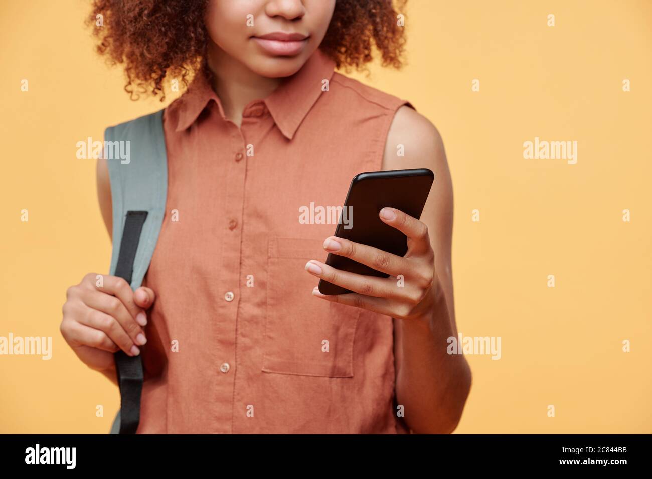 Close-up of black student girl holding strap of satchel and scrolling ...