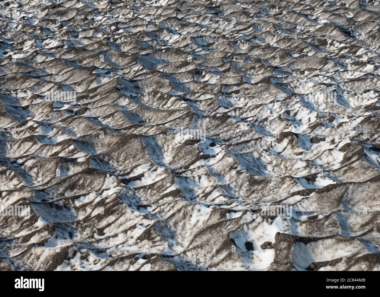 close up snow dunes with black volcanic lava sand with reflection of ...