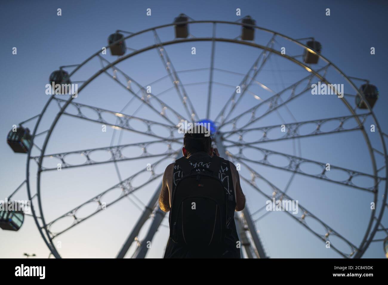 Low angle shot of the back of a male photographing the Ferris wheel ...