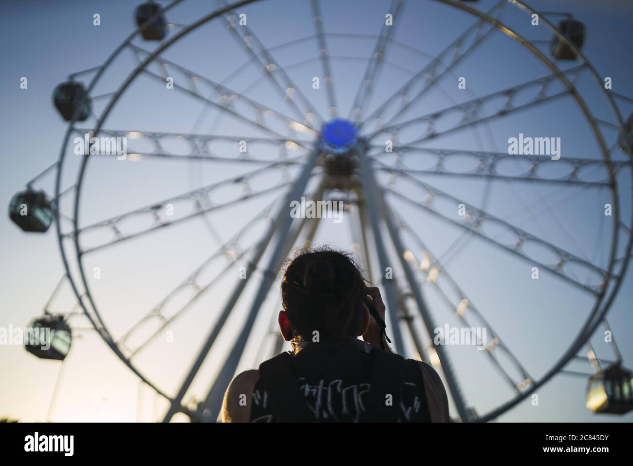 Low angle shot of the back of a male photographing the Ferris wheel ...