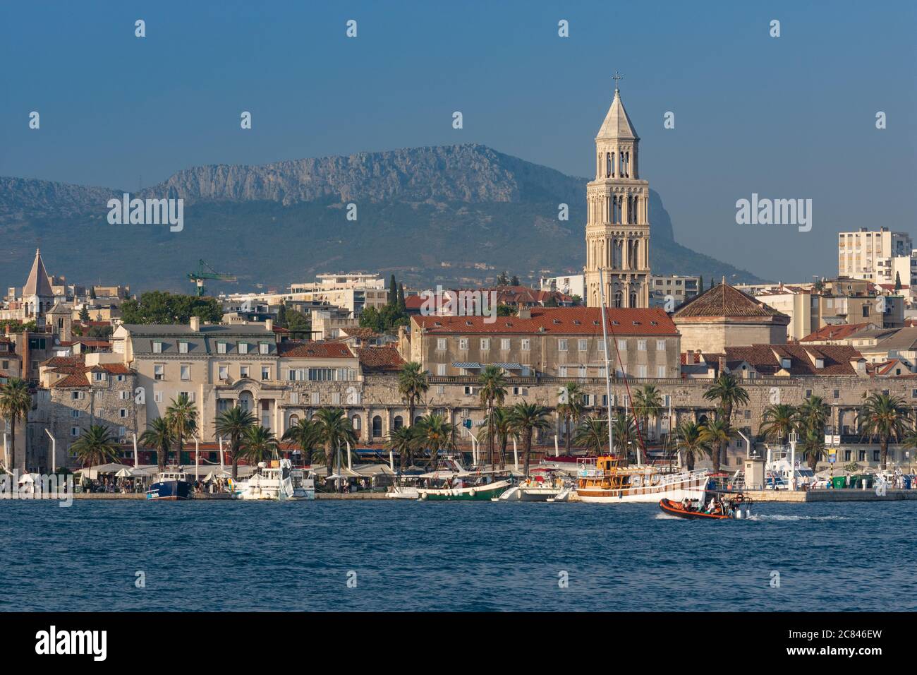 Split, Croatia - August 15 2018: Evening sun casts a warm glow over sea ...