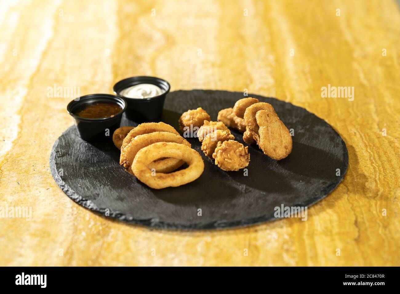 Closeup shot of chicken nuggets on a black round board on a wooden ...