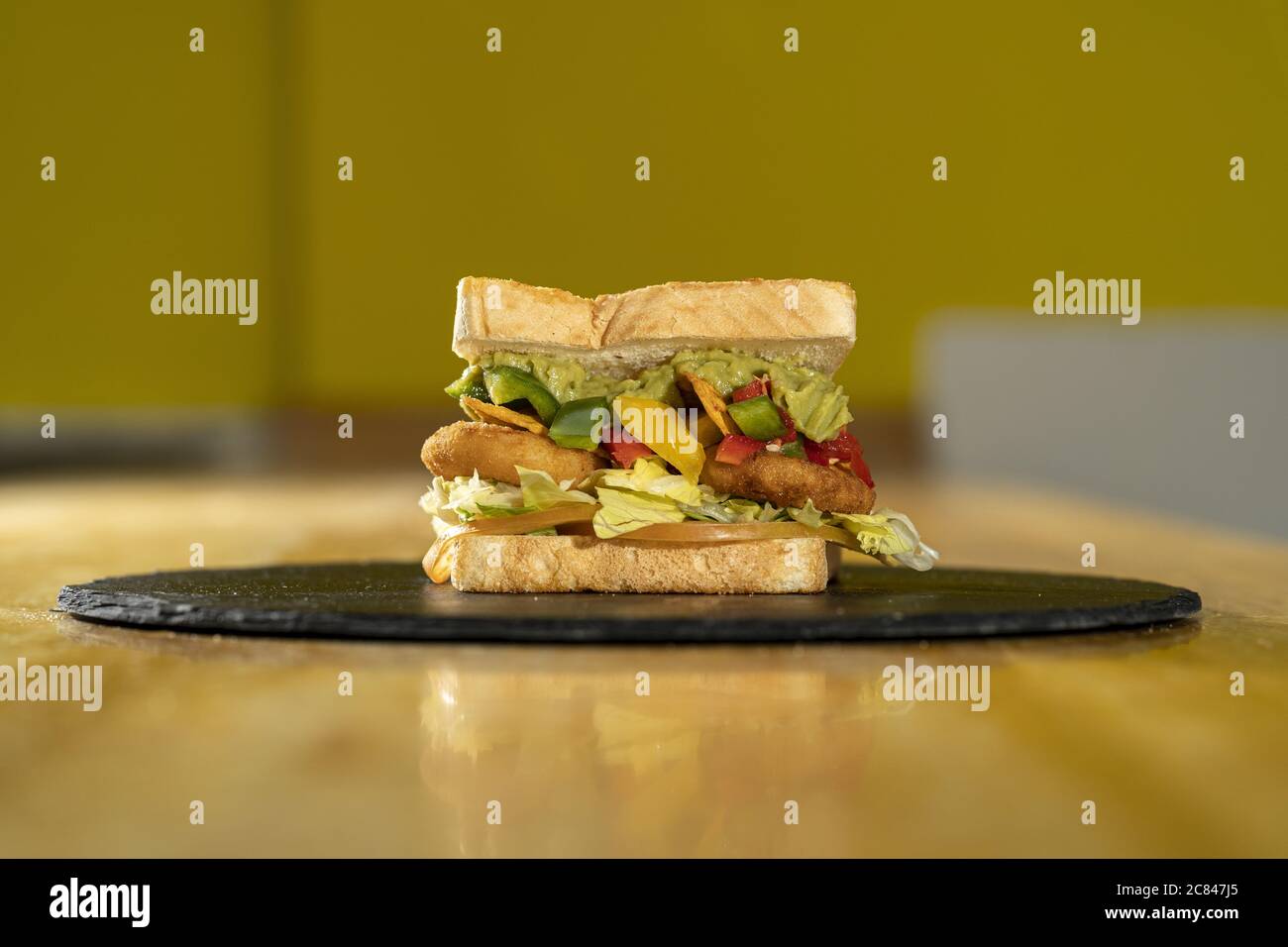 Closeup shot of a sandwich with toast bread and vegetables on a black ...