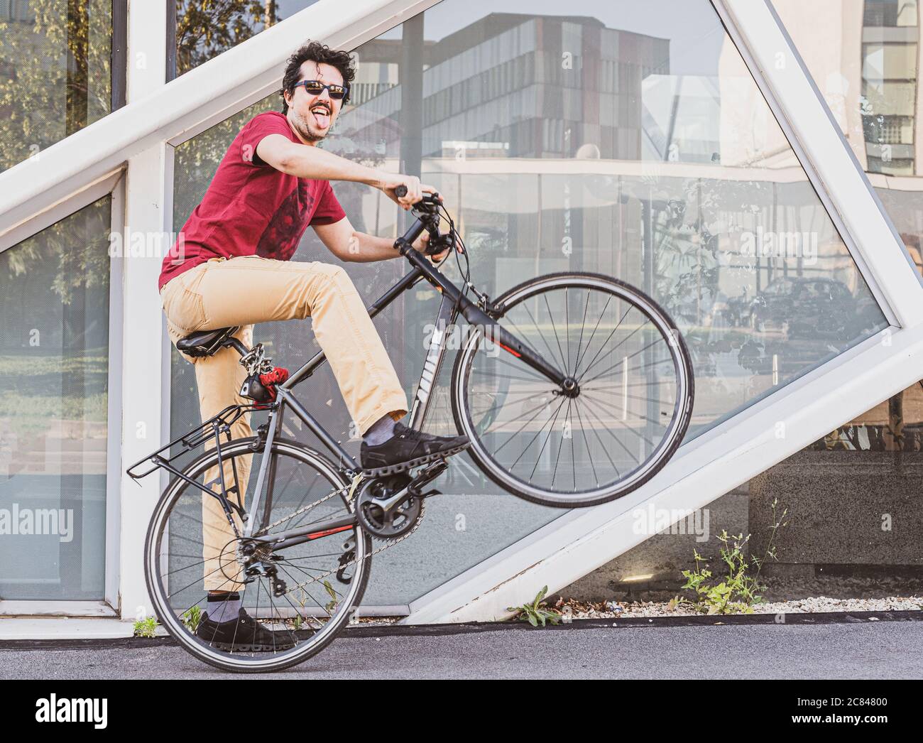 exuberant young man rides his bike, enjoys playing with his bike ...