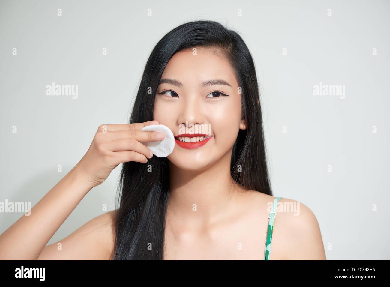 Happy woman caring about her fresh healthy skin of face with cotton pad ...