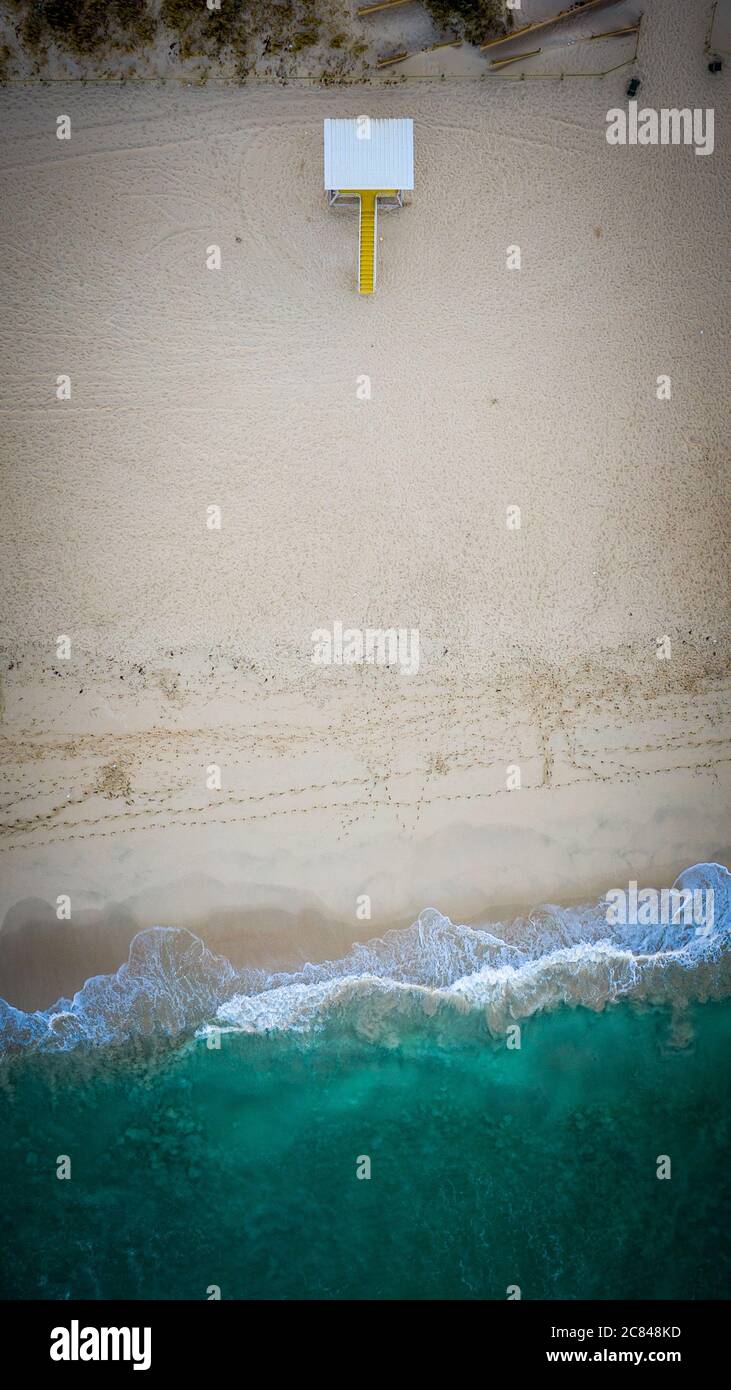 Vertical aerial view of a beautiful beach with splashing sea waves ...