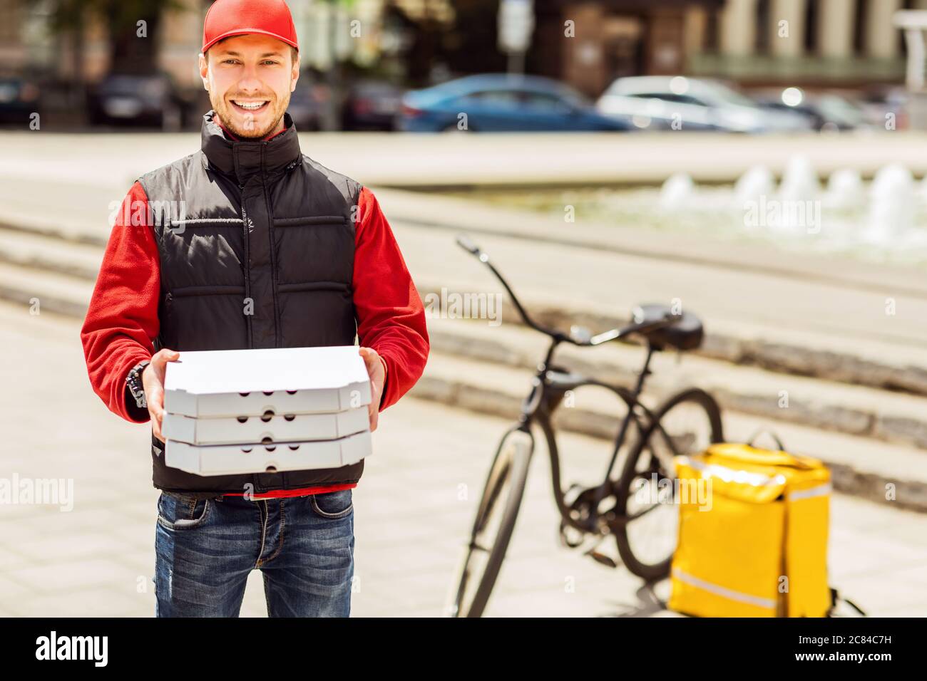 Delivery Courier Holding Pizza Boxes Smiling To Camera Standing Outside ...