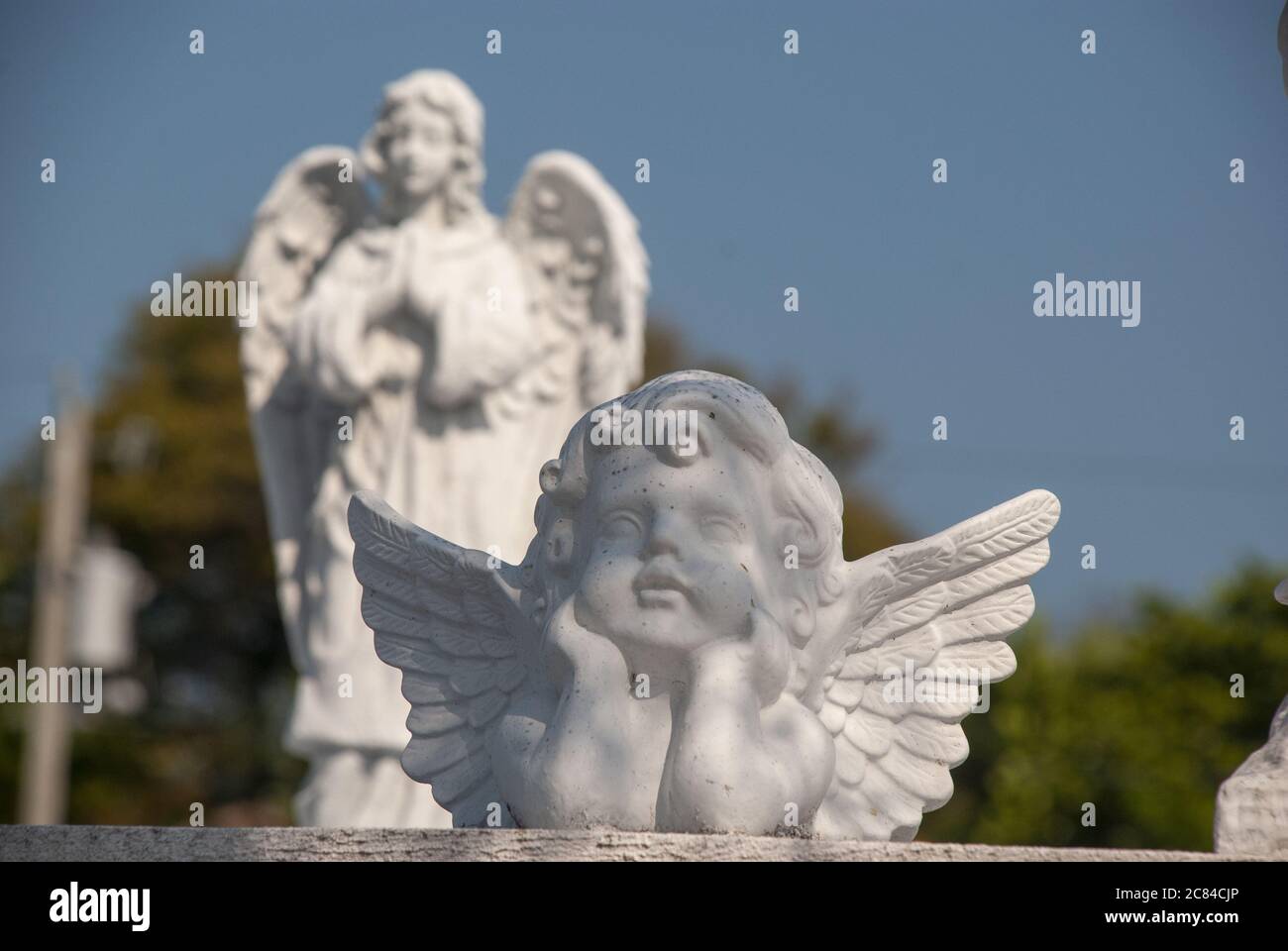 Selective focus shot of a baby angel statue with a blurred female angel ...