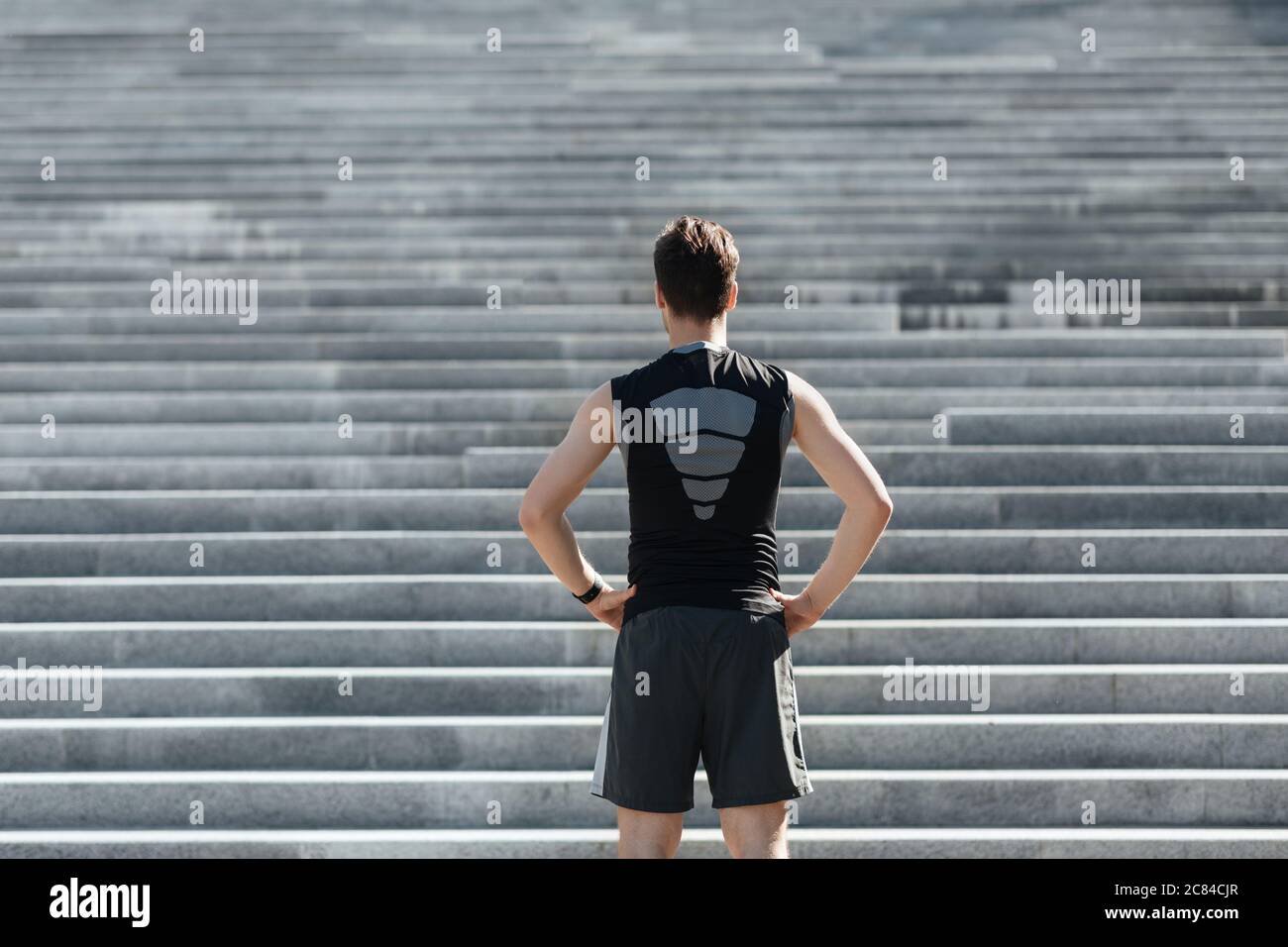 Start of ascent up. Sportsman in sportswear looks at high stairs Stock ...
