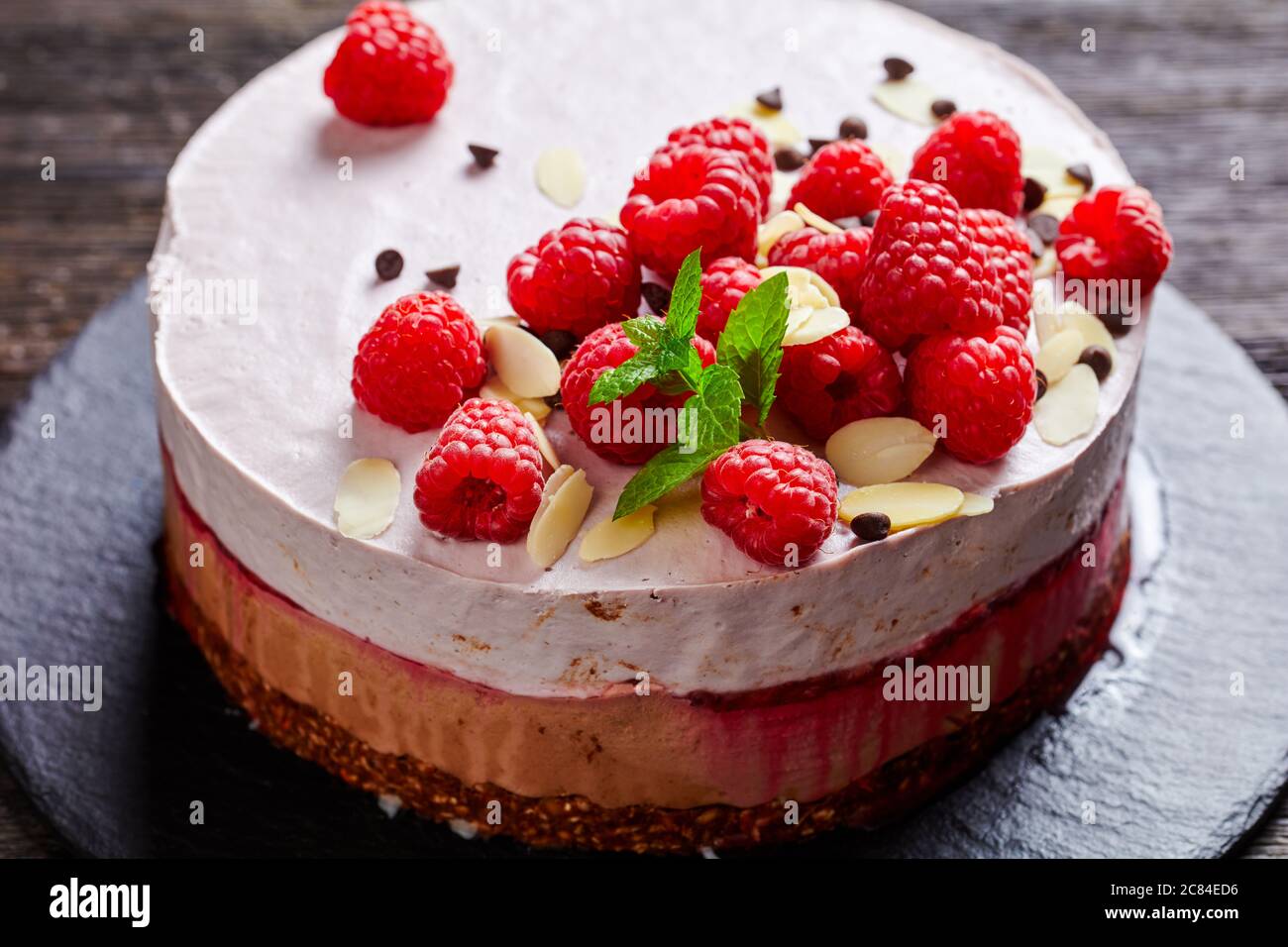 raspberry ice cream cake on a slate black plate on a dark wooden table ...