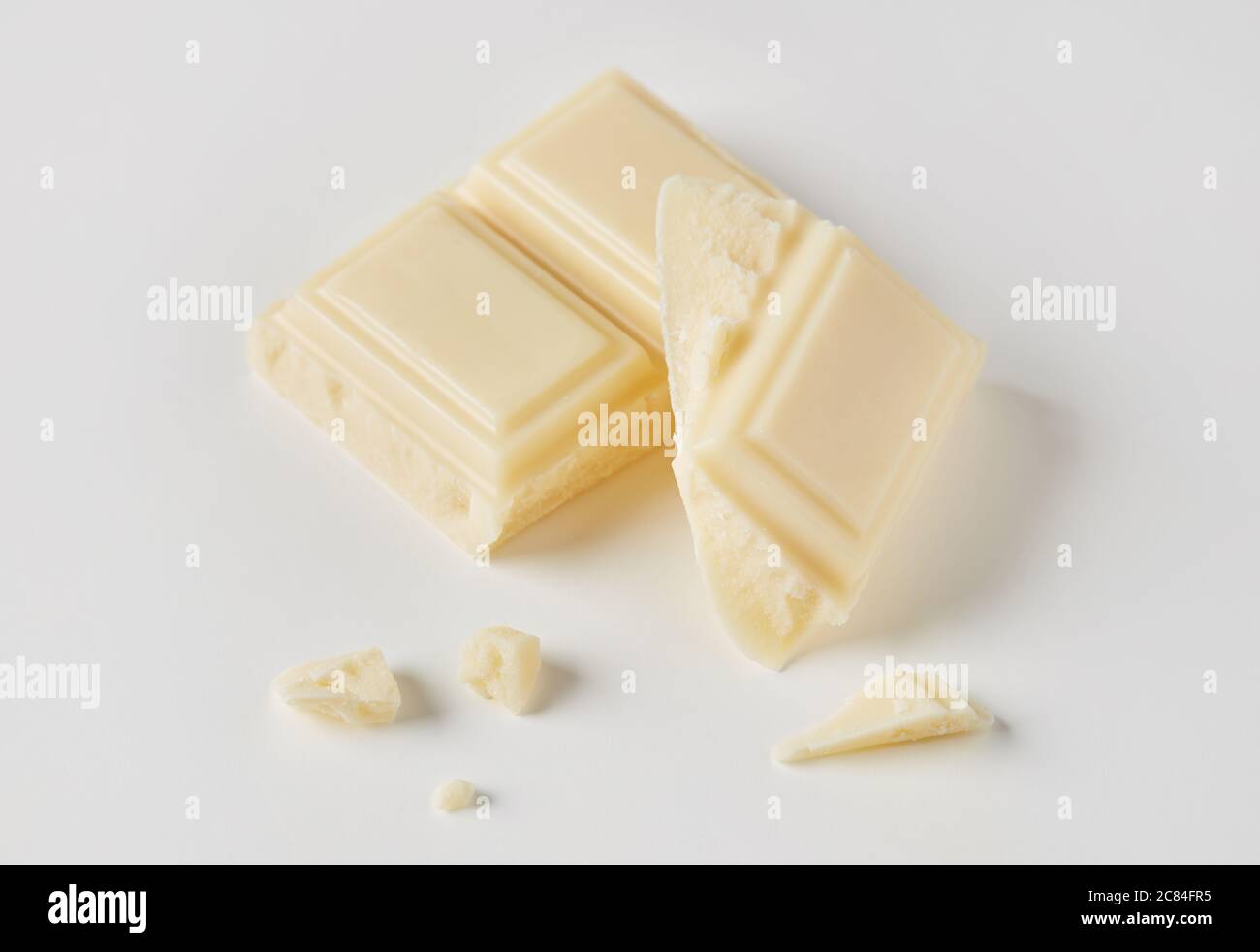 White chocolate chunks on white background Stock Photo - Alamy