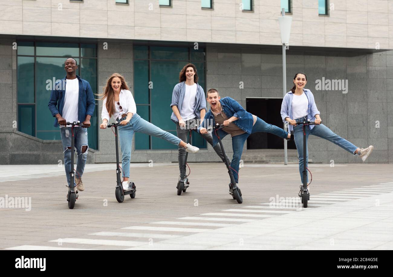 Friends having fun riding motorized kick scooters Stock Photo - Alamy