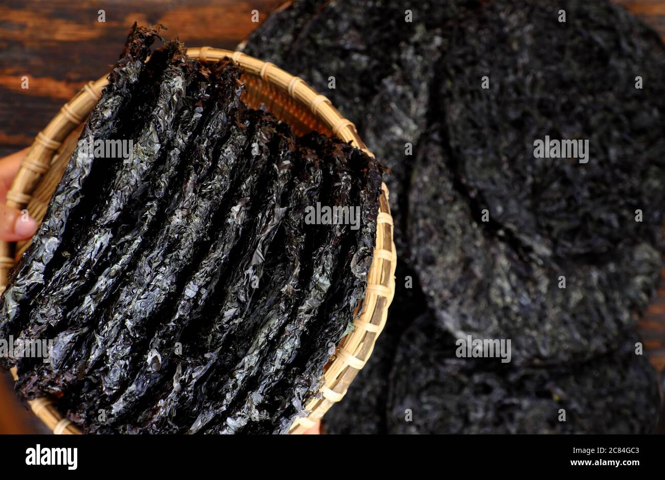 Top view group circle sheet dried black seaweed in basket, woman hand ...
