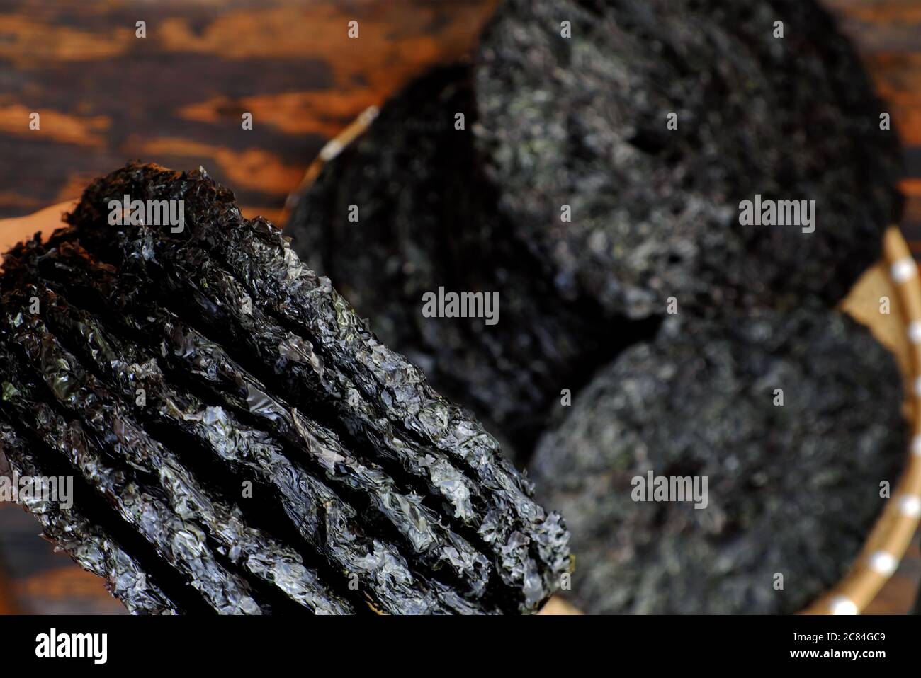 Top view group circle sheet dried black seaweed in basket, woman hand ...