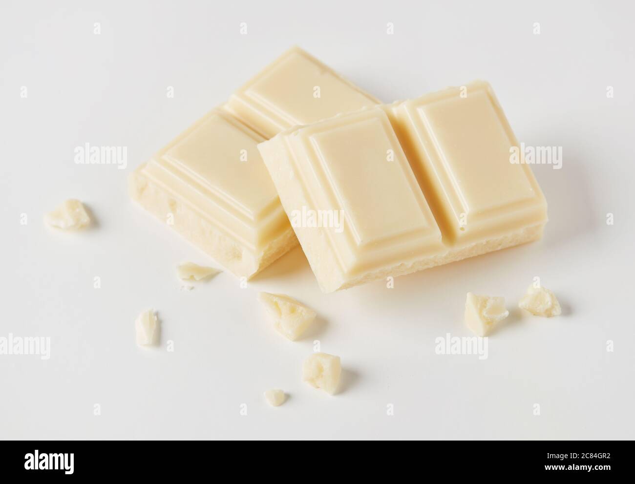 White chocolate chunks on white background Stock Photo - Alamy