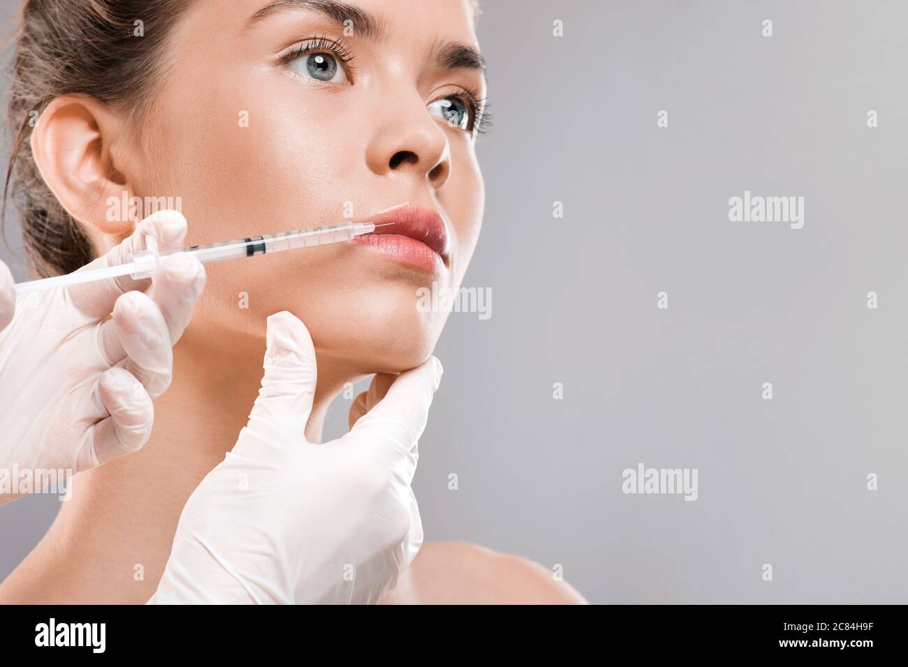 Lip injection for young lady over grey studio background Stock Photo ...