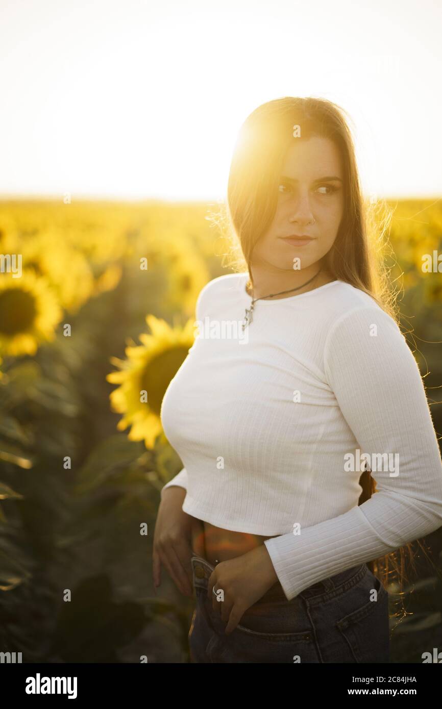 Vertical shallow focus shot of pretty European female in a sunflower ...