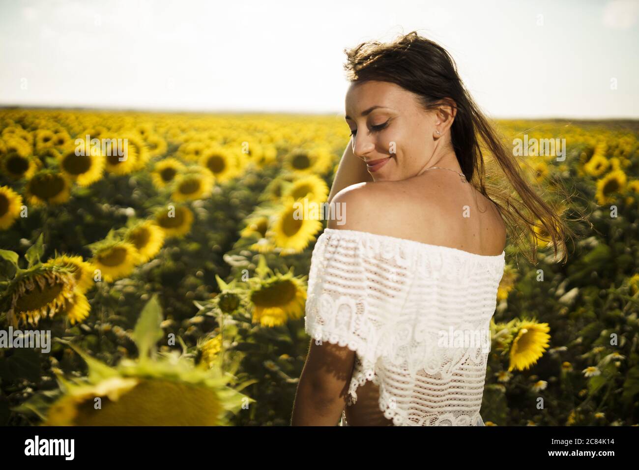 Shallow focus shot of pretty Caucasian female in a sunflower field at ...