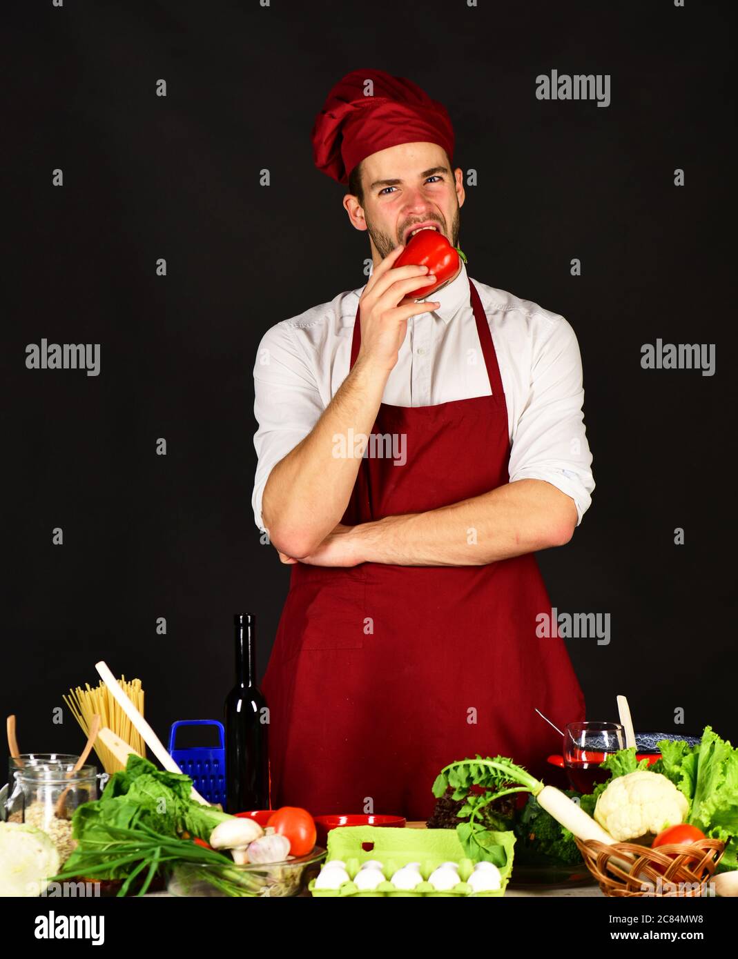 Cook works in kitchen near table with vegetables and tools. Chef with ...