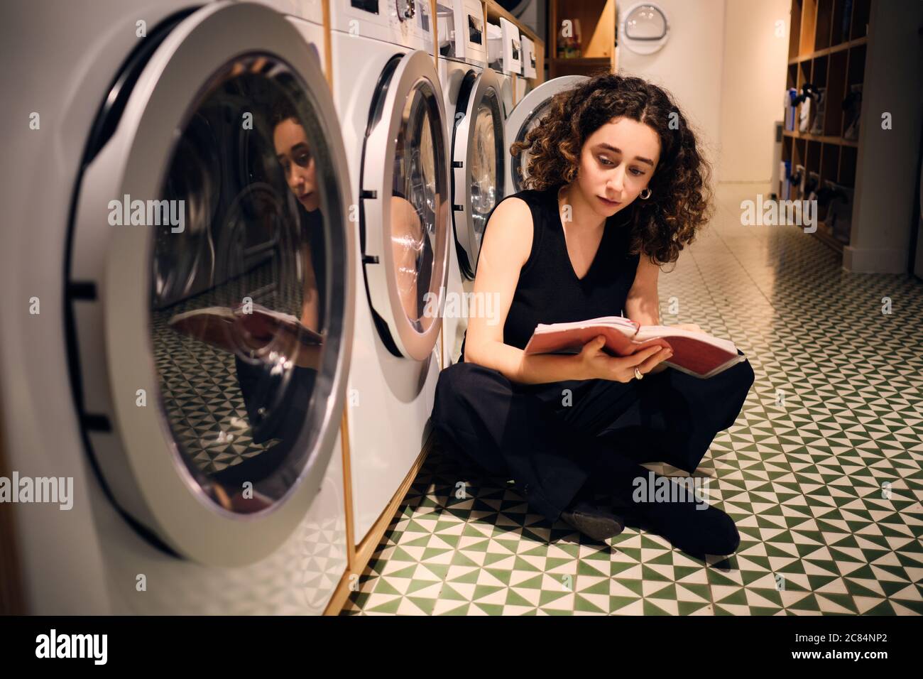 Attractive brunette girl thoughtfully reading book waiting washing in ...