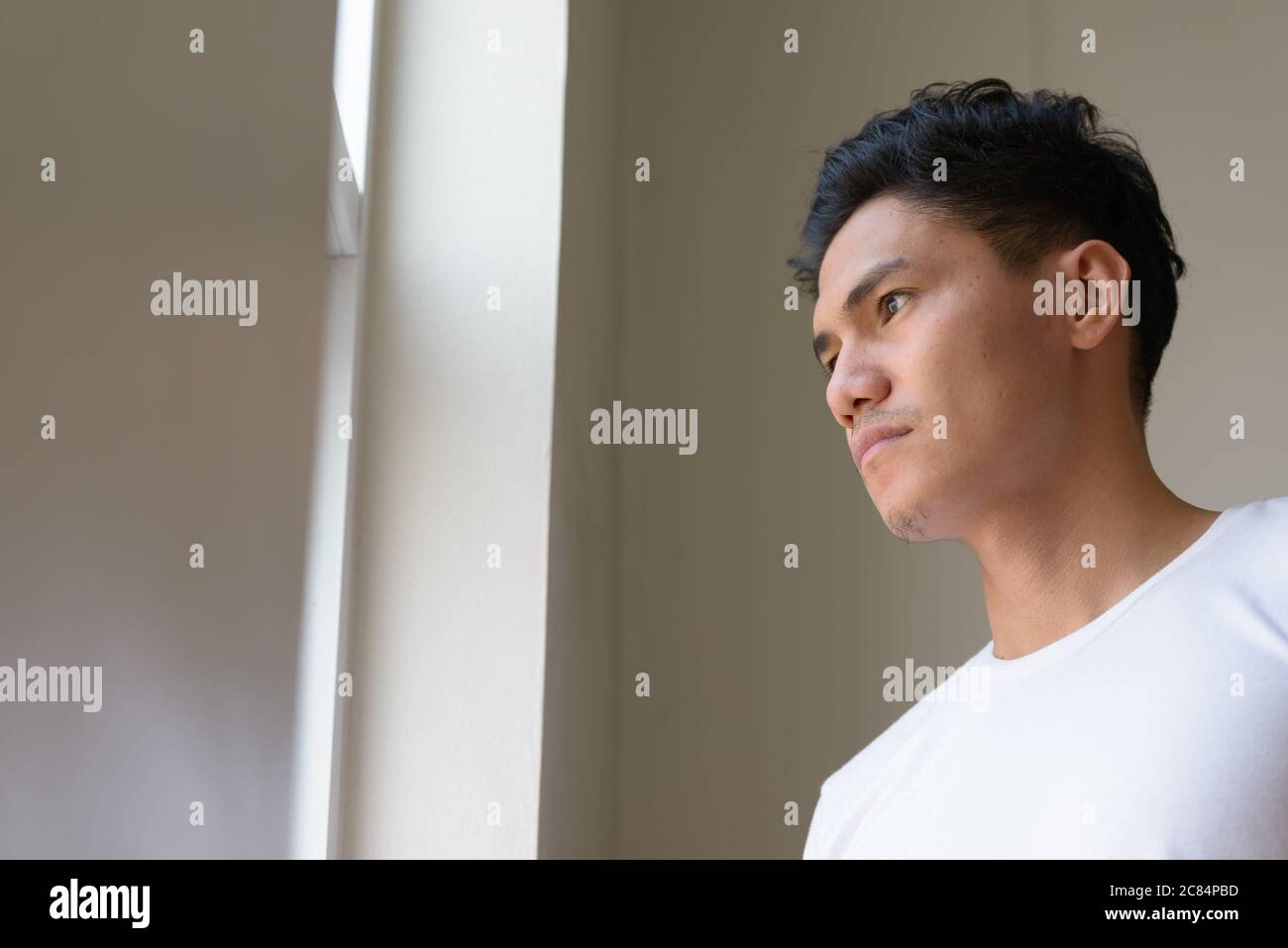 Face of handsome Asian man looking outside the window indoors Stock ...