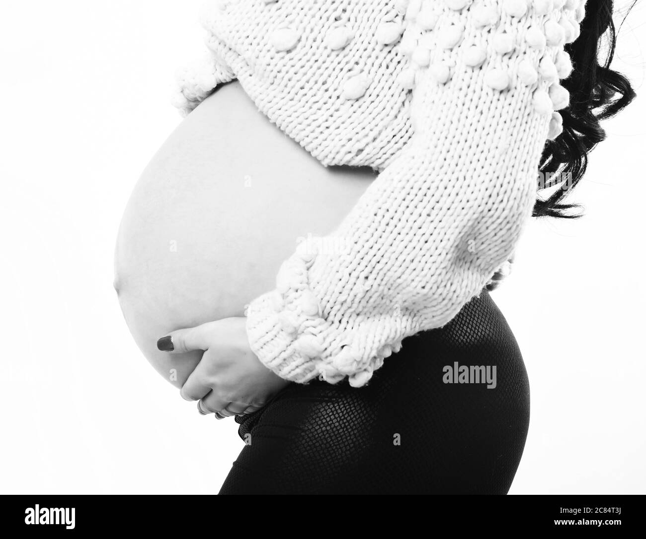 female hands of pregnant woman stroking her belly in beige knitted ...