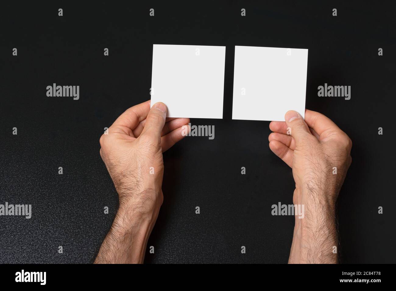 hand holding two blank notes paper or image frame on dark background ...