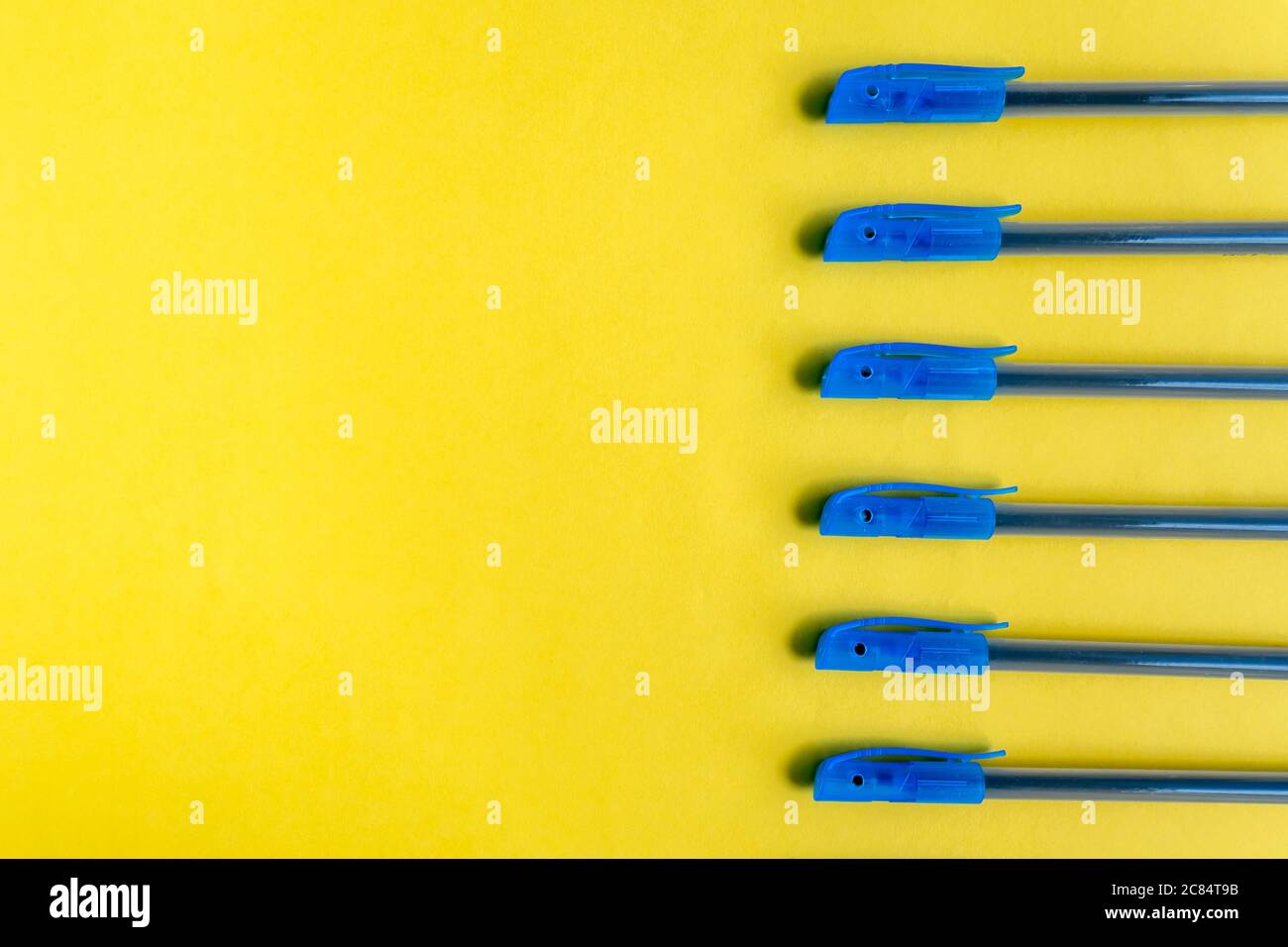 Blue ballpoint pens on a yellow background on the right side. Flat lay ...