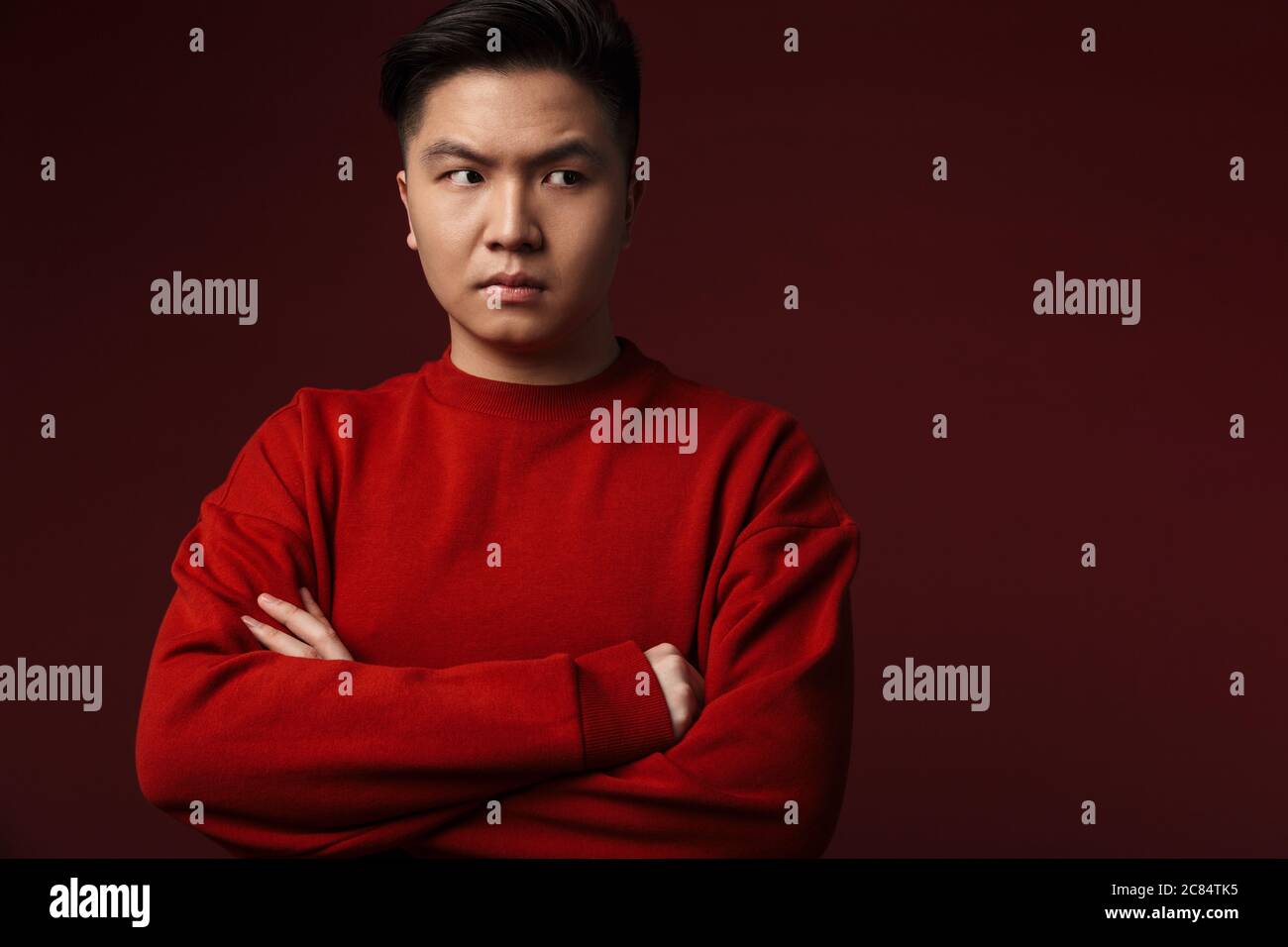 Image of displeased young asian man posing with hands crossed isolated ...